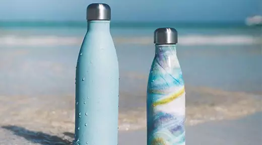 Rong ukuran botol banyu S'well ing pantai, siji botol biru lan siji pelangi