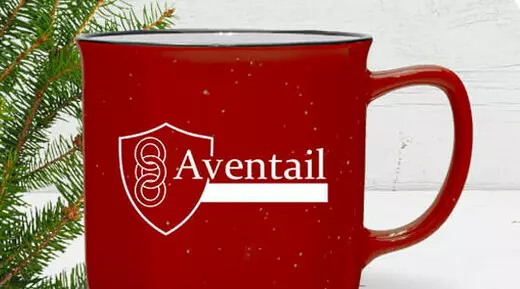 正面有 Aventail 標誌的紅色咖啡杯，位於木牆和松樹前