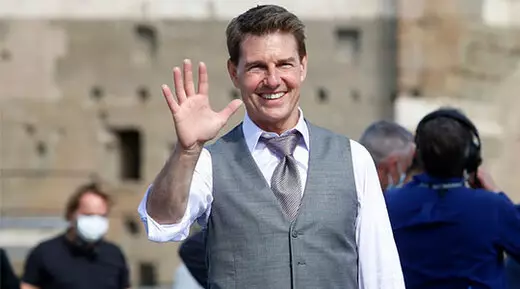 Oṣere Tom Cruise n rẹrin musẹ ati fifun awọn ololufẹ rẹ lori ṣeto fiimu naa