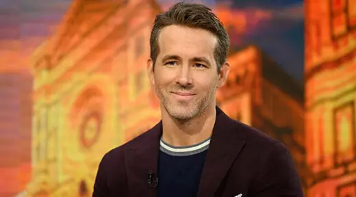 Ryan Reynolds ni aṣọ ni iwaju apẹrẹ ile osan